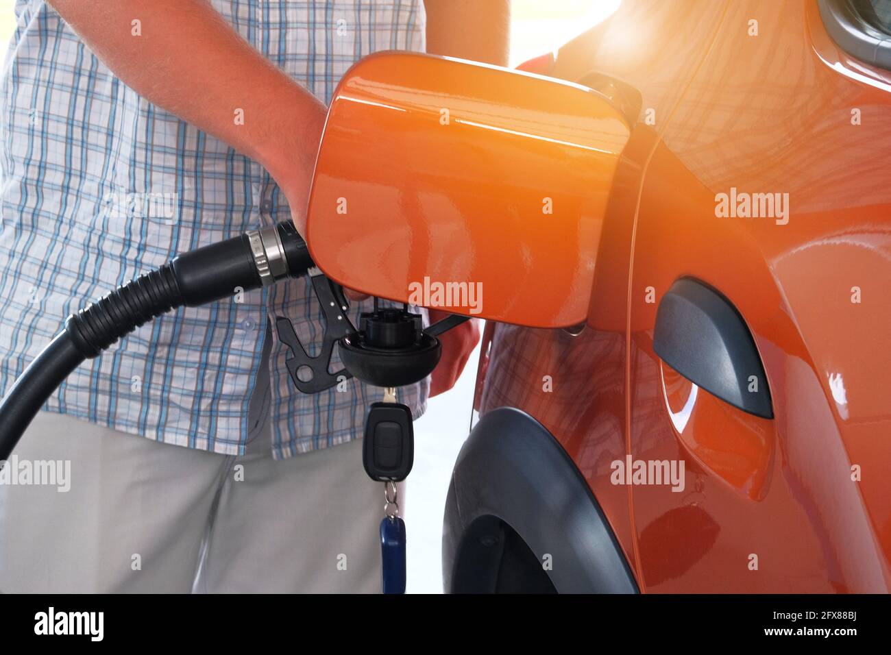 Pumping gasoline fuel in orange car at a gas station. To fill car with ...