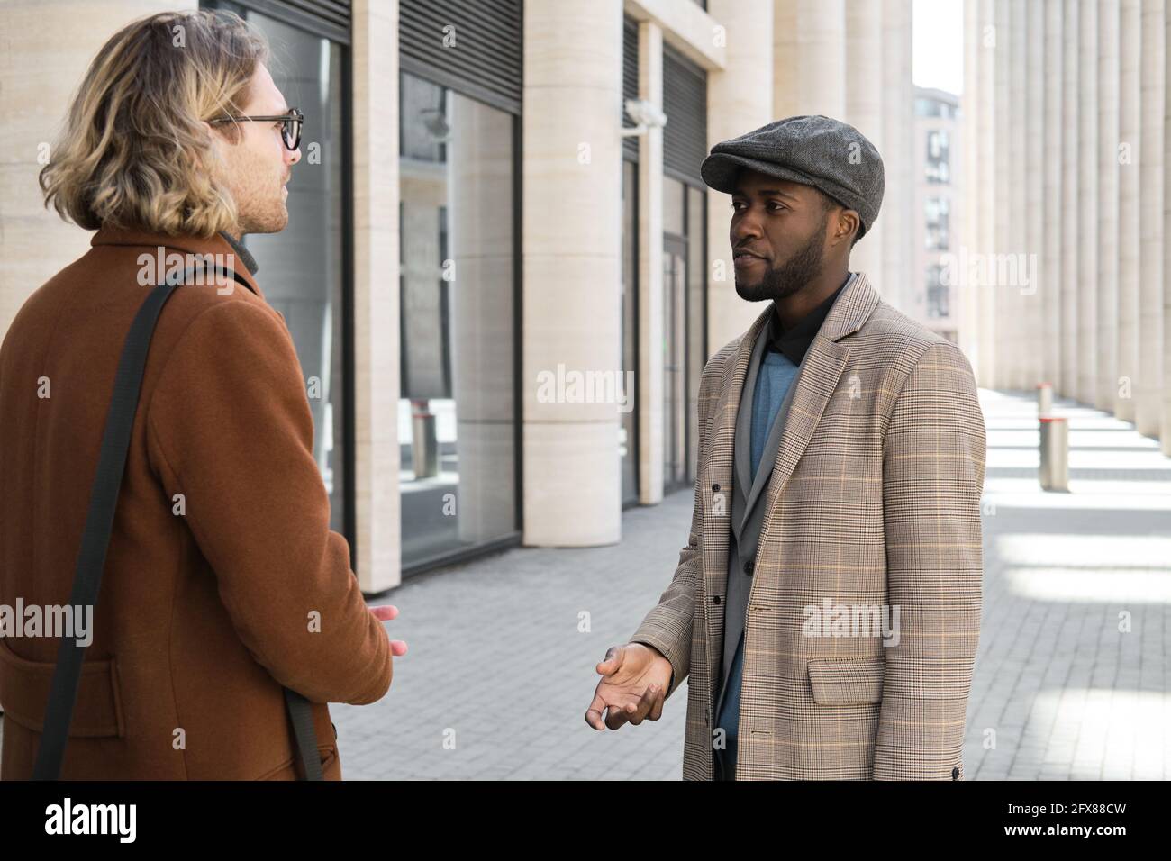 Two young men talking to each other while standing on the street Stock Photo - Alamy