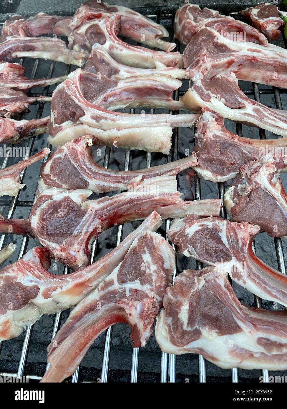 Vertical shot of raw beef legs cooking on a rack on an open grill Stock ...