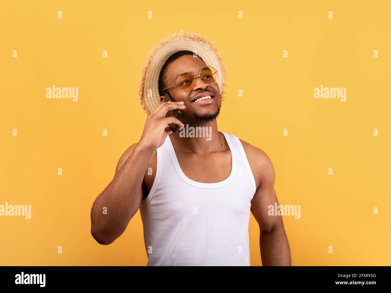 Positive black man in summer wear calling on smartphone, having ...