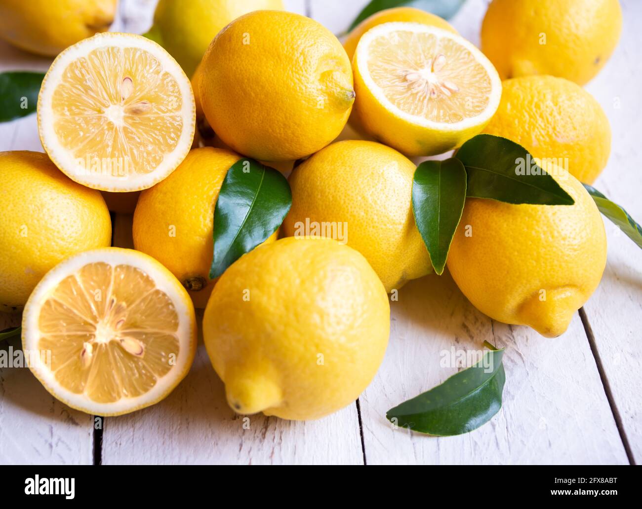 Fresh and ripe lemons with leaves on white wood Stock Photo - Alamy