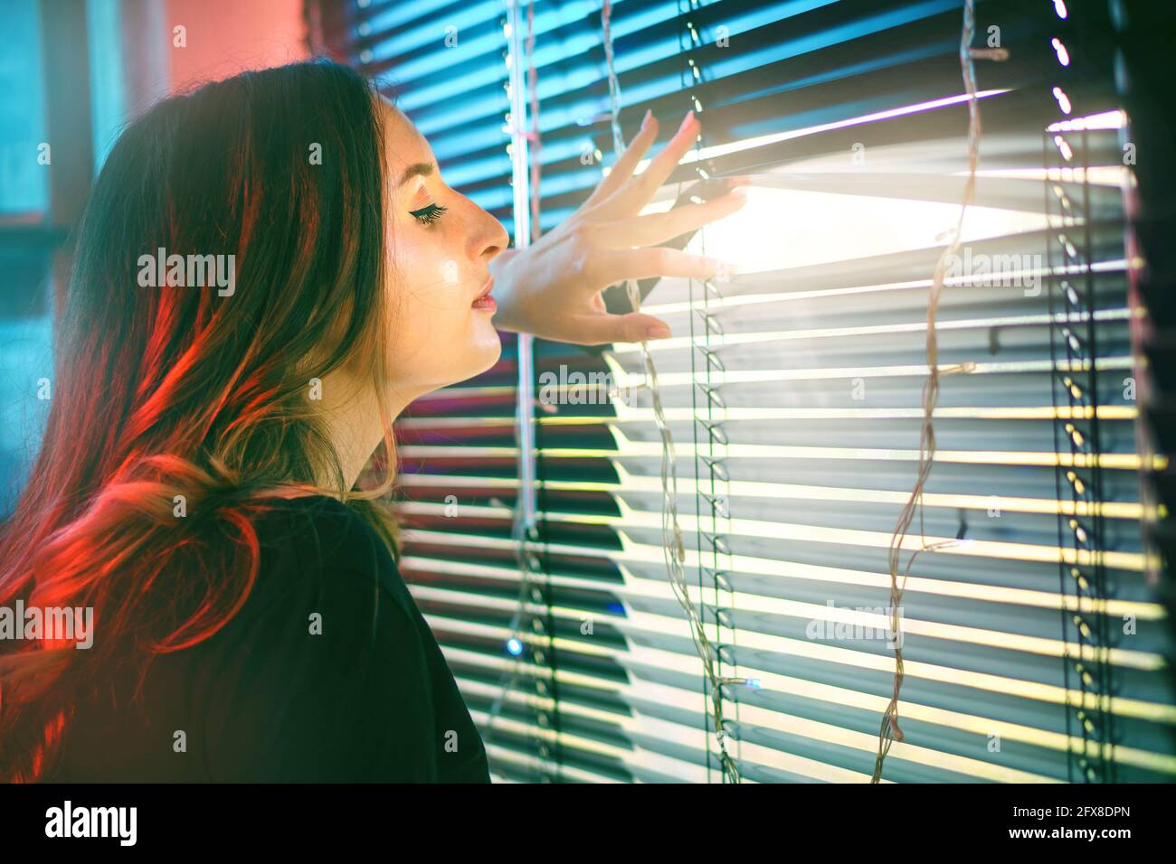 Person in self-isolation. Woman looks through blinds outside window ...
