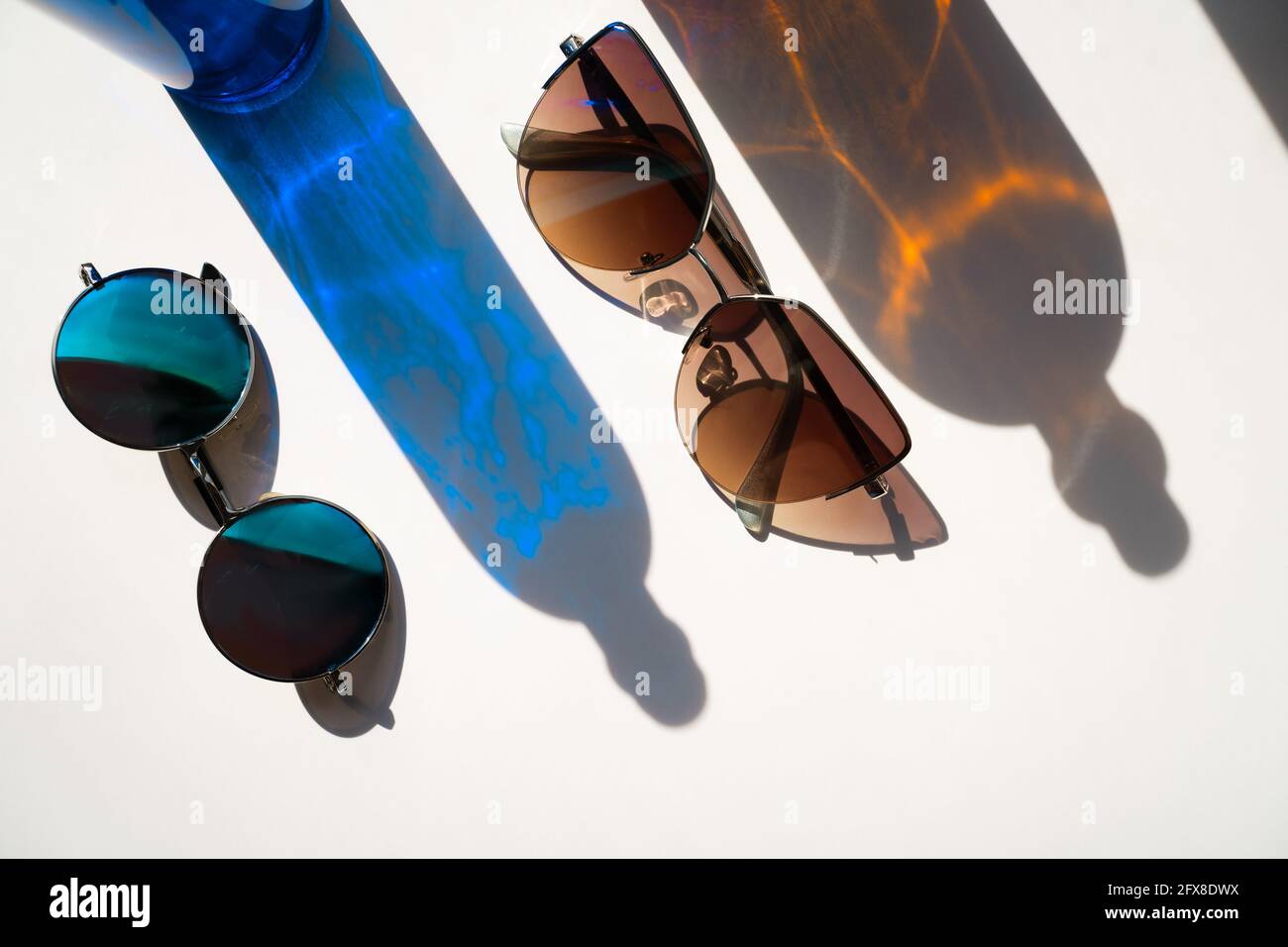 Blue and brown sunglasses with glass bottle reflections on white ...