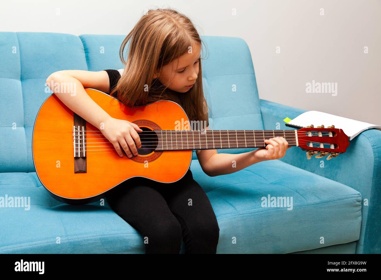 Little girl, young school age child playing guitar, focused kid ...