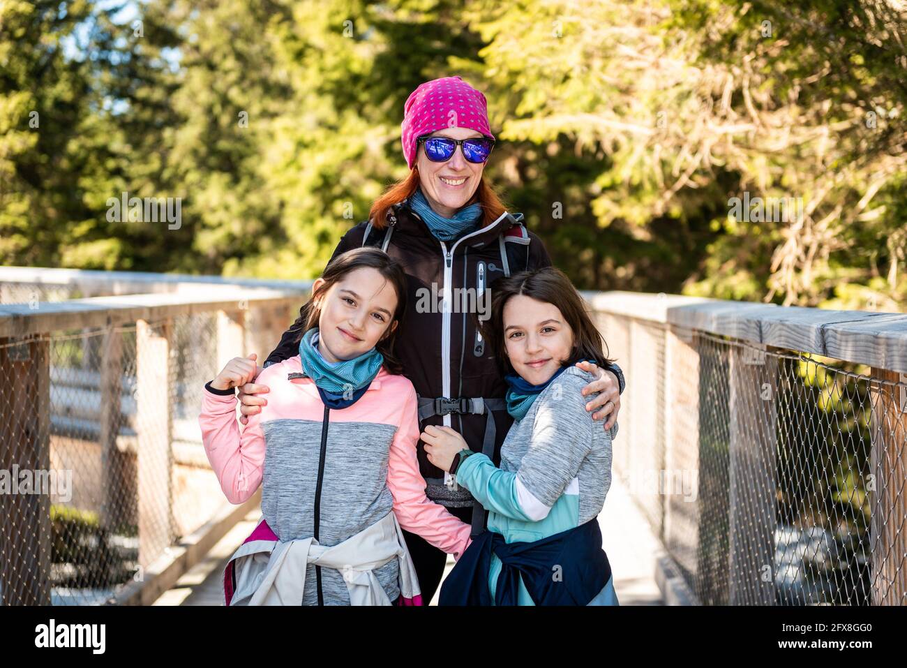 Portrait of family visiting wooden treetop observation deck walkway in ...
