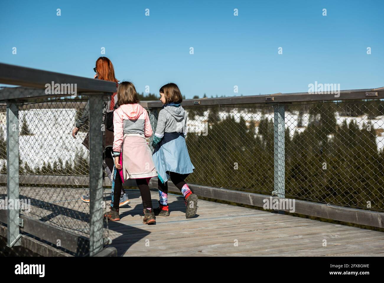 Family people walking wooden treetop observation deck walkway in winter ...