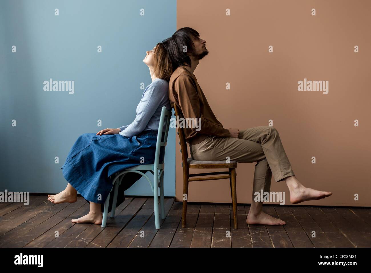 Guy and girl sit back to back on a chair. Background is divided into ...