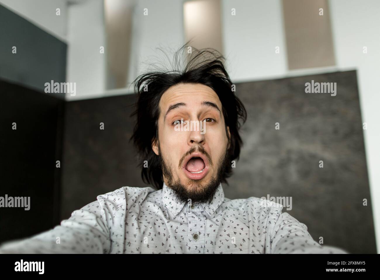 Guy blows with wind he looks at camera, guy has a beard mustache and ...