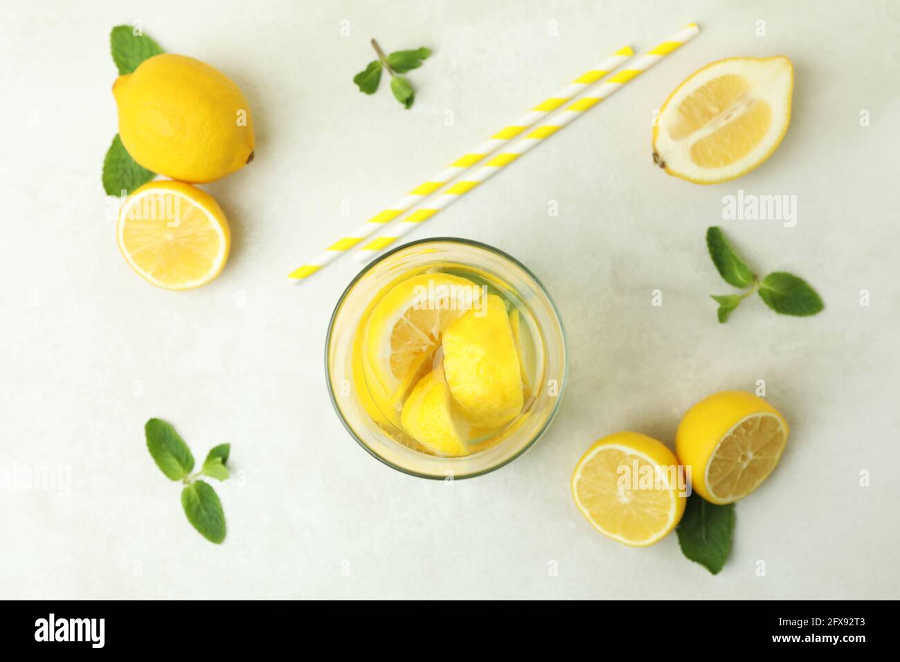 Glass of lemonade, straws and lemons on white textured table Stock ...