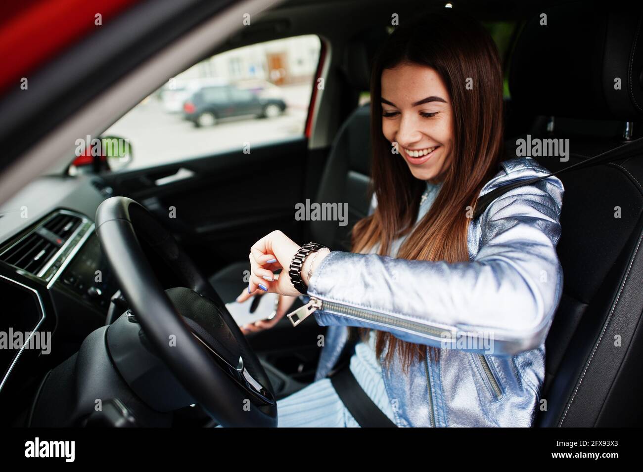 Gorgeous woman sitting inside car interior, look in her watch Stock ...