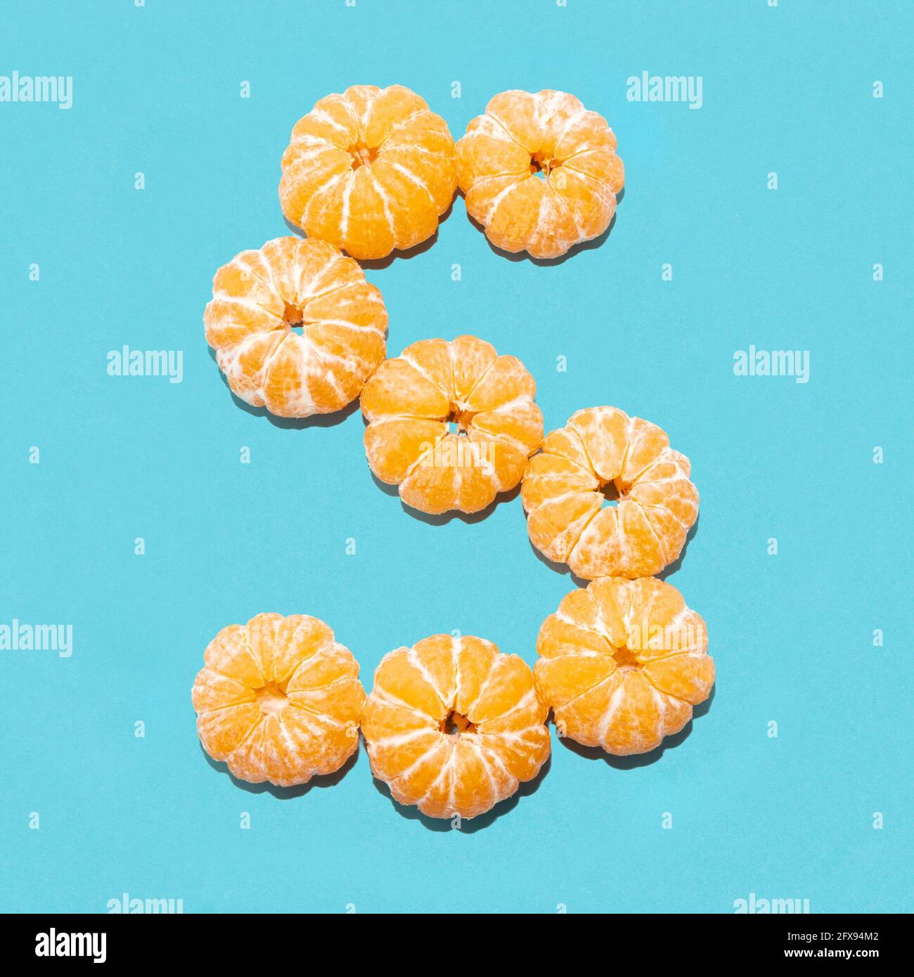 Creative layout of the letter S from peeled tangerines on a blue ...