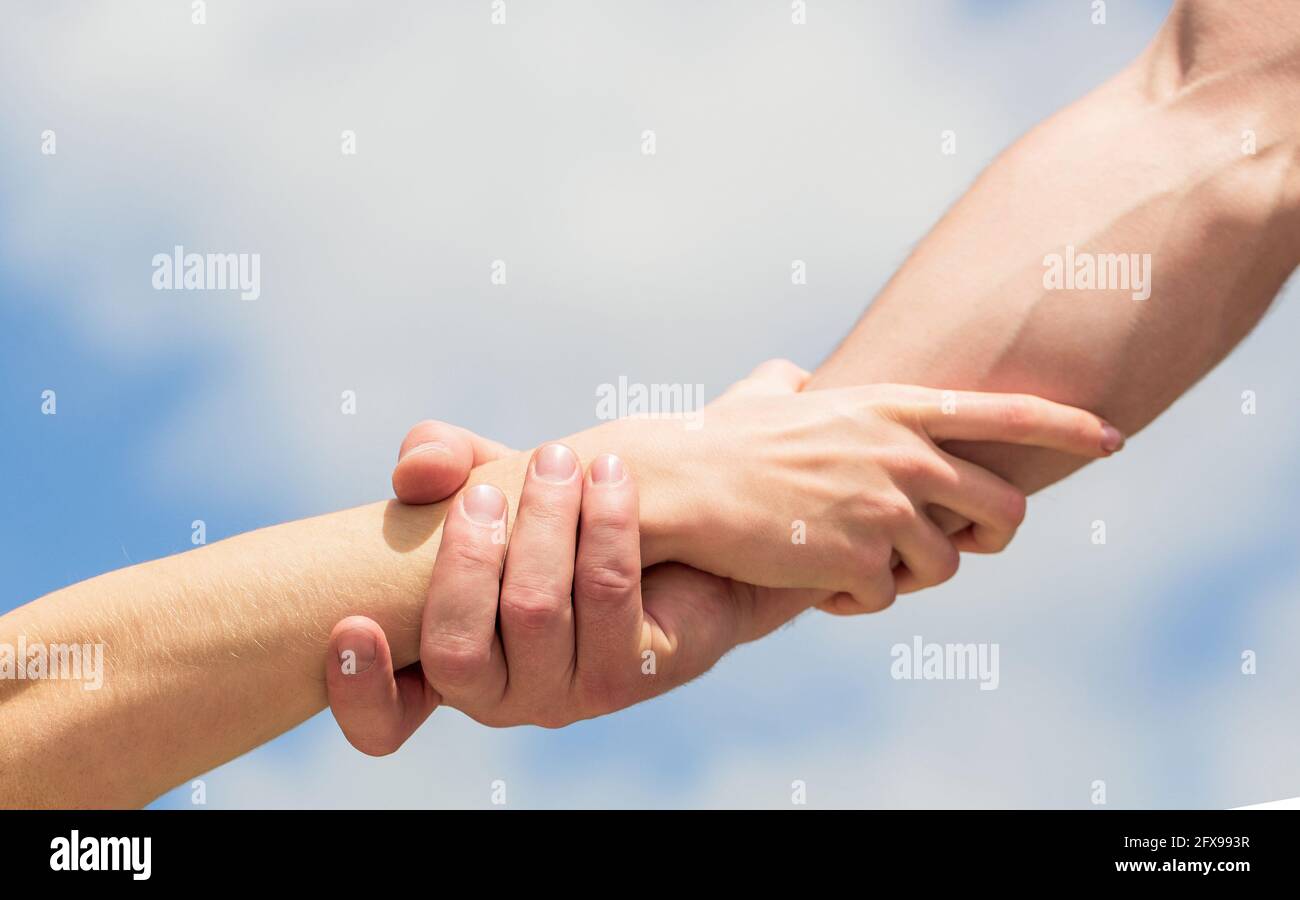 Giving a helping hand. Hands of man and woman on blue sky background ...