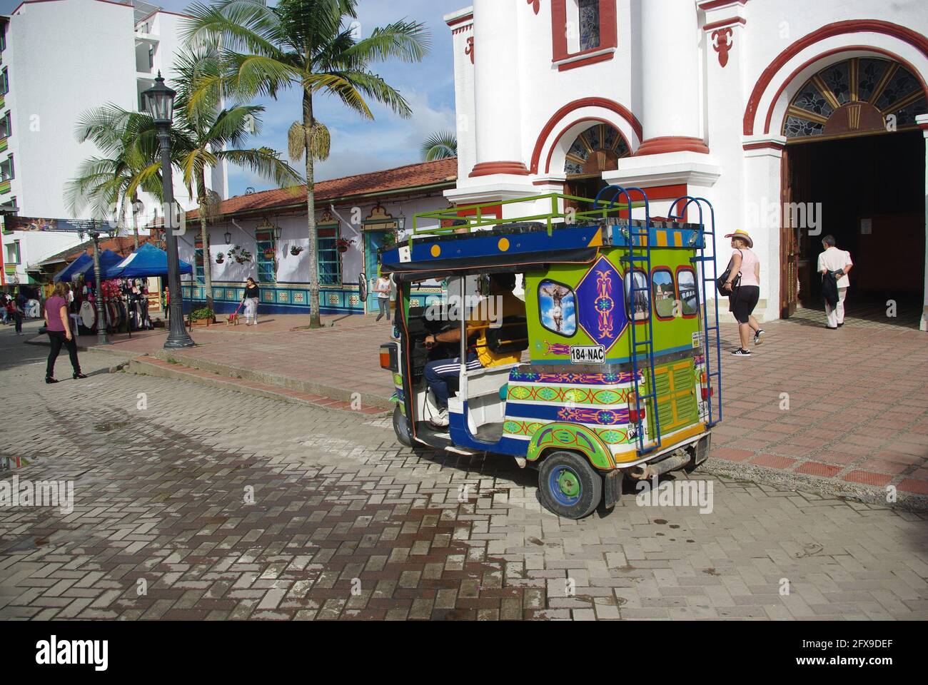 Tuk tuk in main square with Church of Our Lady of Carmen, Guatape ...