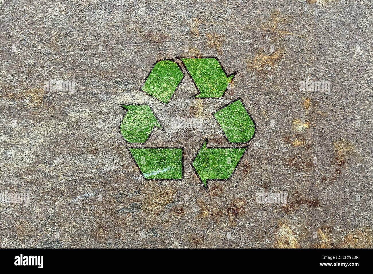 Closeup shot of a green recycling arrow icon on a rusty iron plate ...