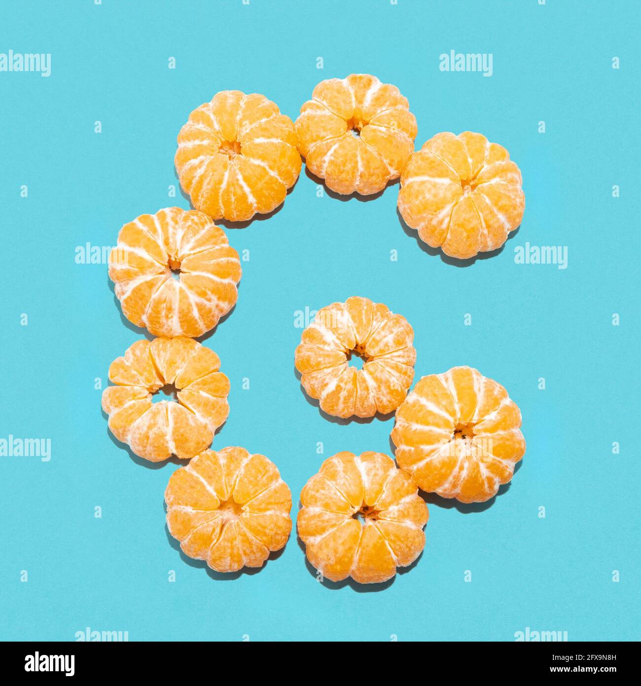 Creative layout of the letter G from peeled tangerines on a blue ...