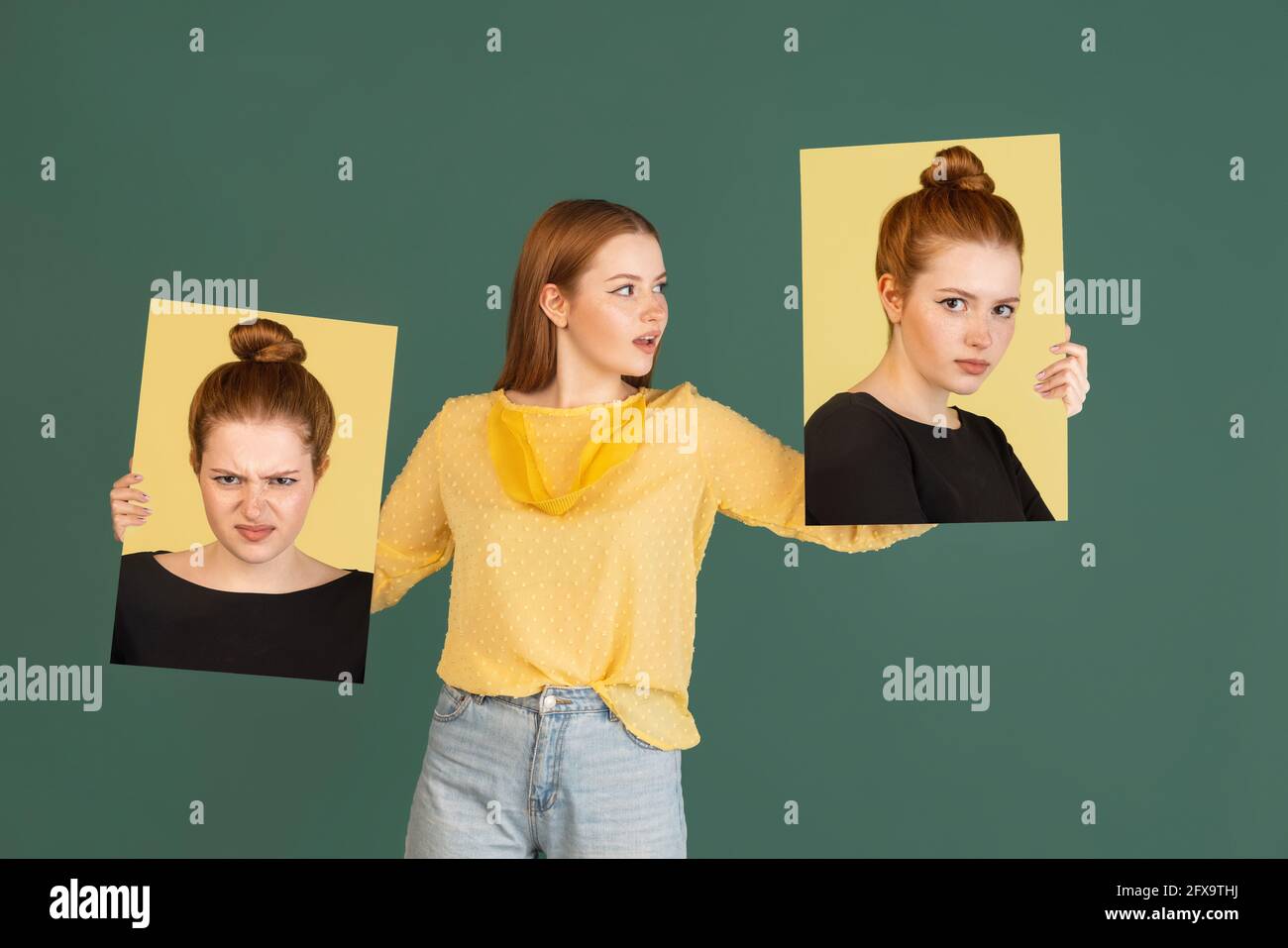 Young red headed girl holding her portraits isolated over green studio ...