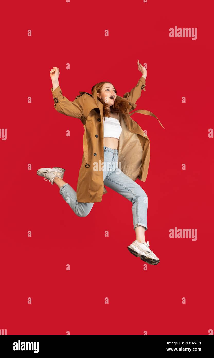 Young happy girl jumping isolated over red studio background with ...