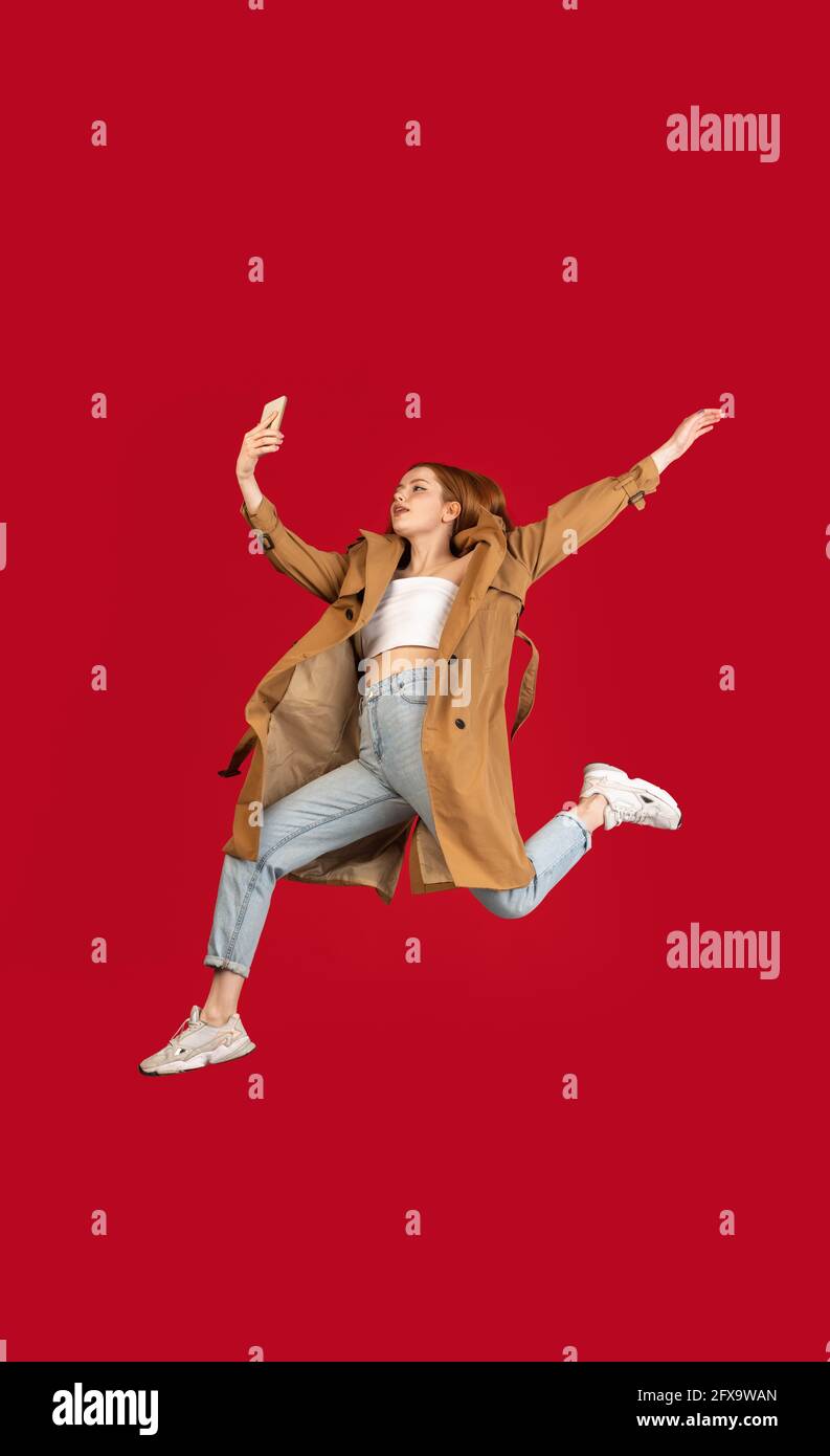 Young happy girl jumping isolated over red studio background with ...