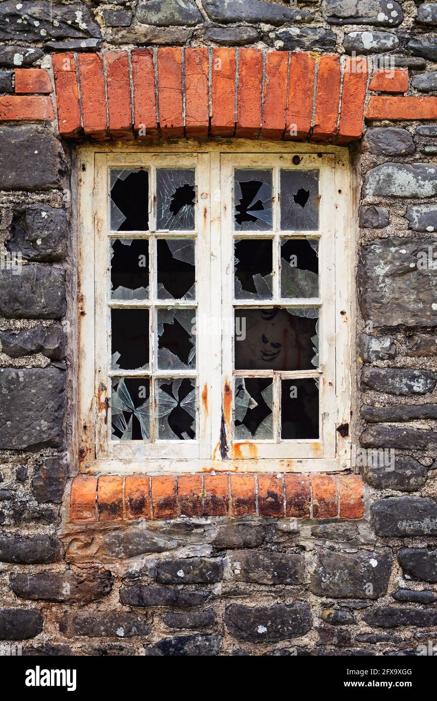 Old sash window, with broken glass and a graffiti of the joker in the ...