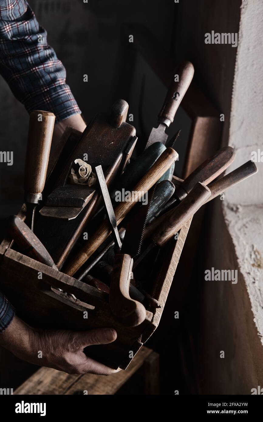 From above anonymous artisan carrying wooden crate with assorted ...