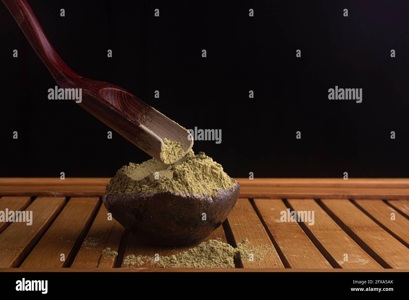 matcha, green tea in clay pot and a wooden spatula sprinkles tea on ...
