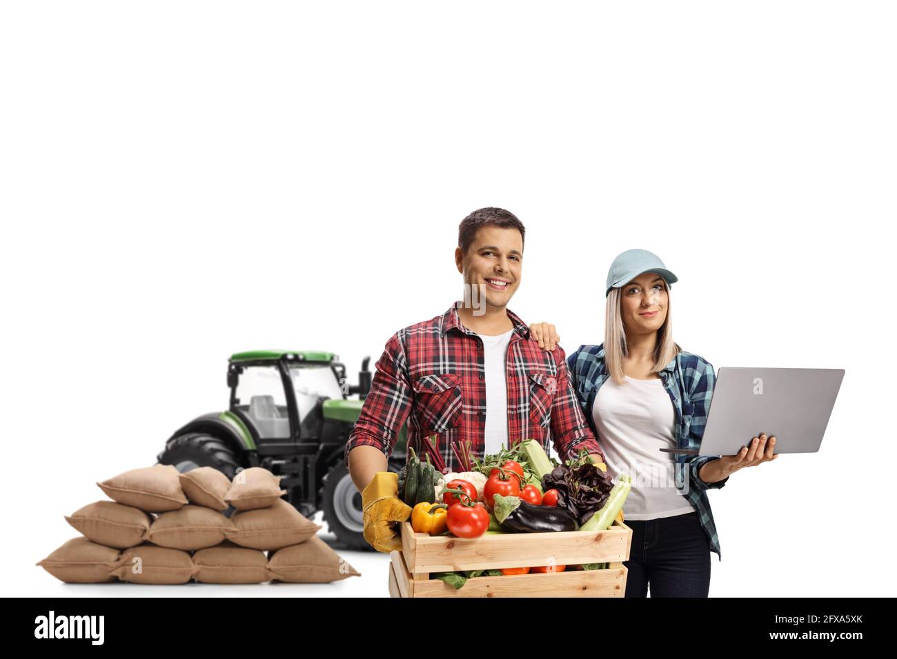 Young farmers with a crate of vegetables and a laptop computer standing ...