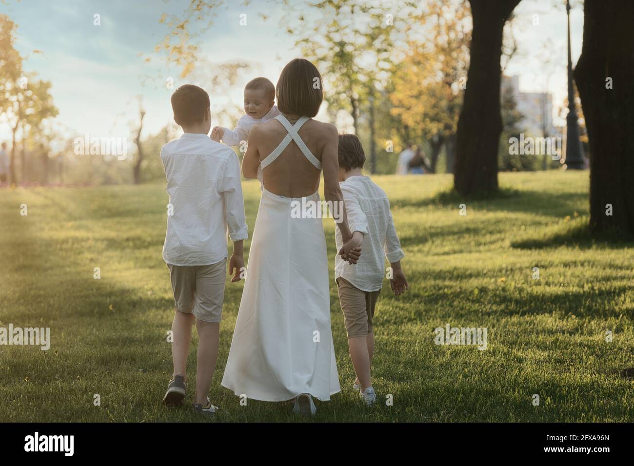 Mother and three children hugging. Happy family sitting outdoor: woman ...