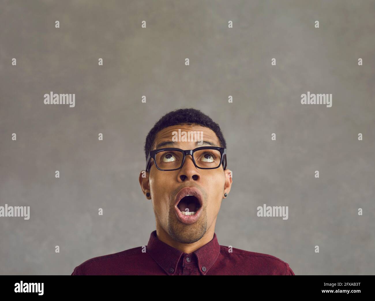 Surprised happy man wearing glasses looking up closeup studio shot ...
