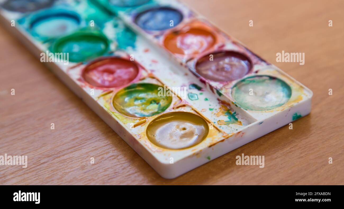 On the table is a used set of multicolored watercolor paints for ...