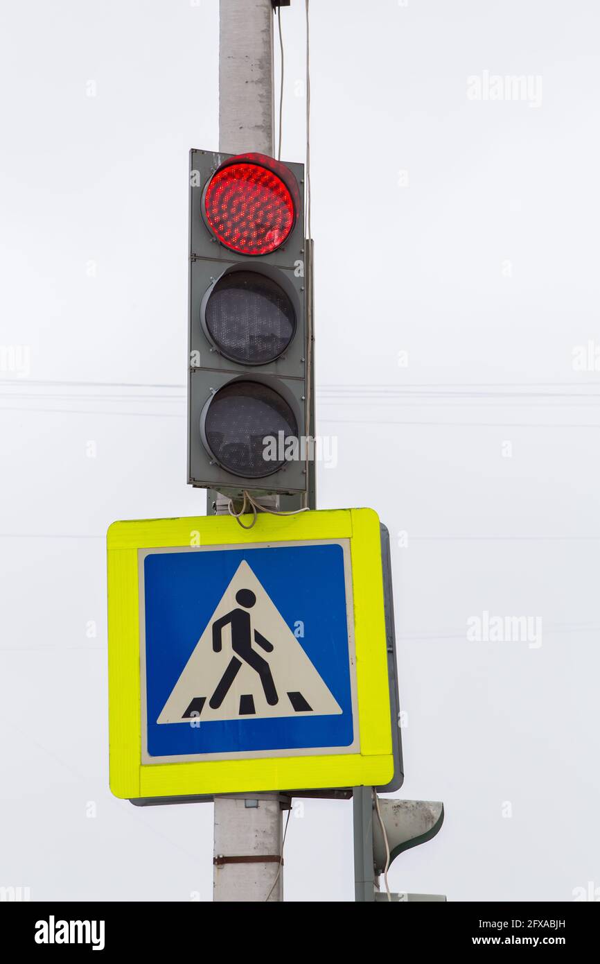 Red traffic light and pedestrian crossing sign are on. Against the ...