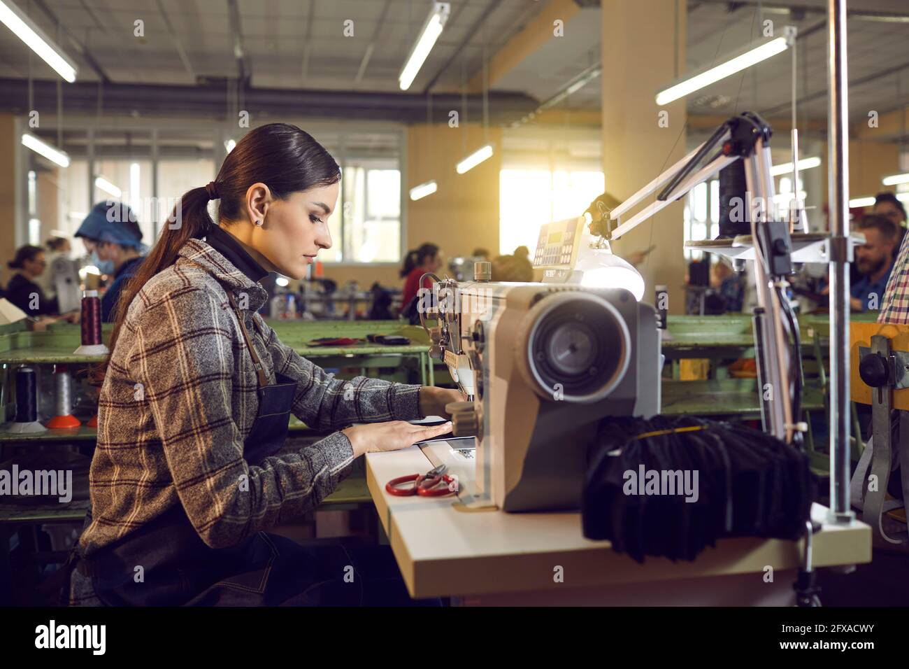 Shoe or clothing factory worker working at a table with an industrial ...