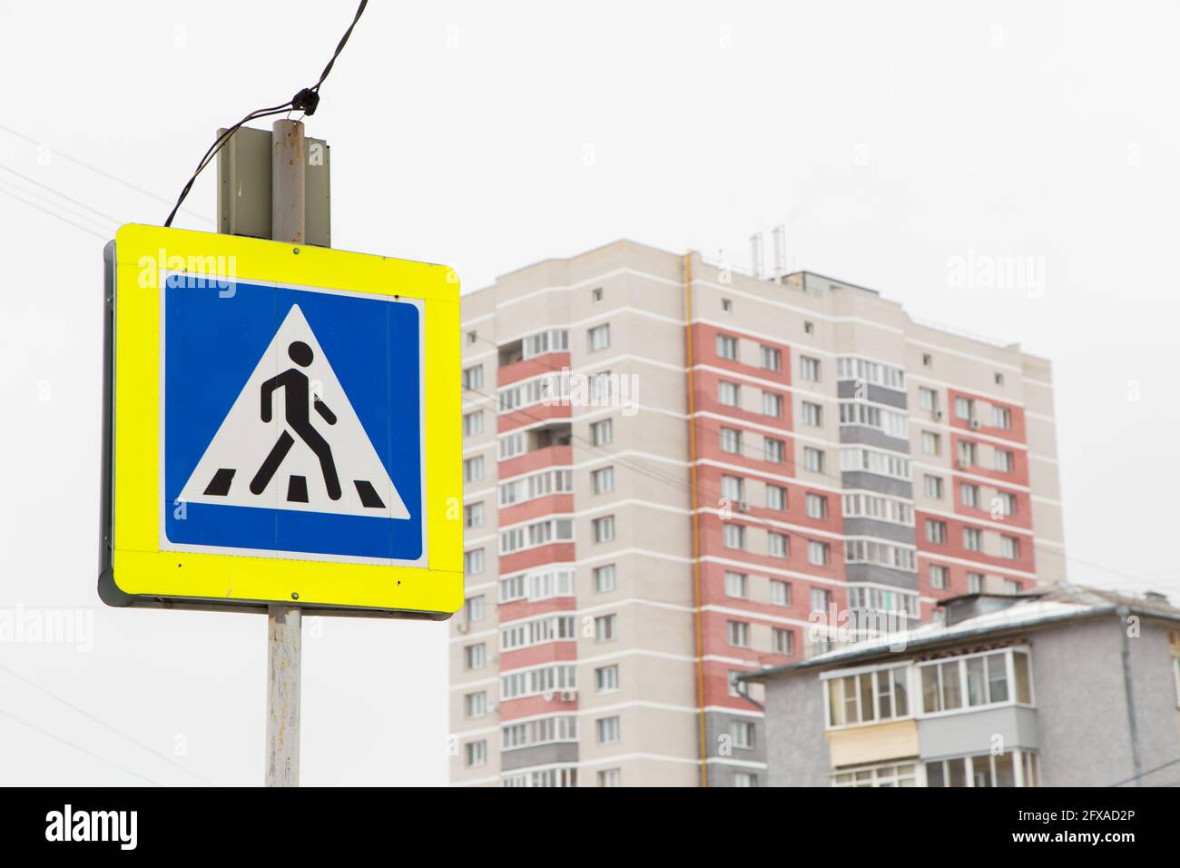 A pedestrian crossing road sign stands next to a high-rise building ...