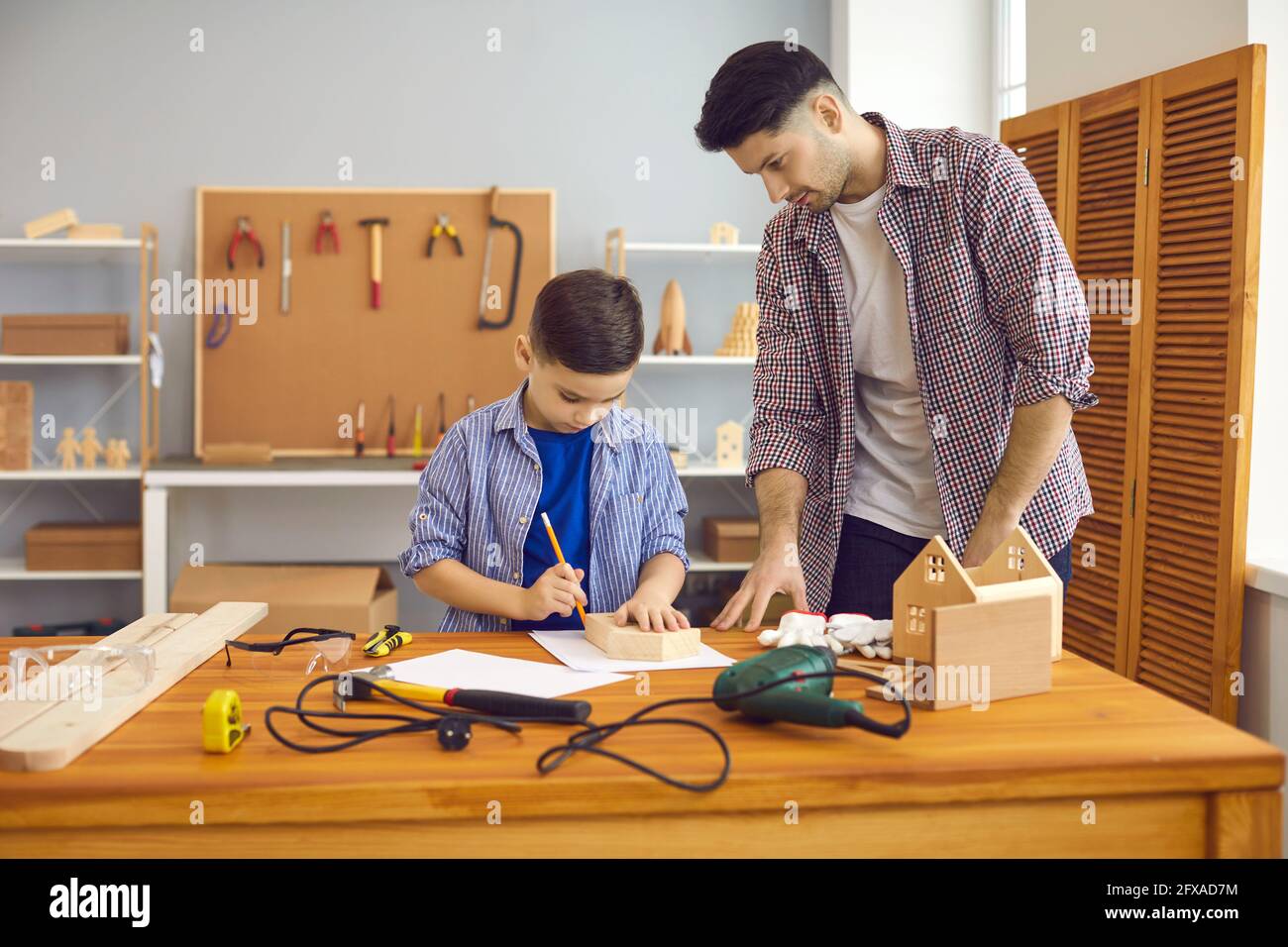 Father and little son building wooden toy house enjoy common hobby at ...