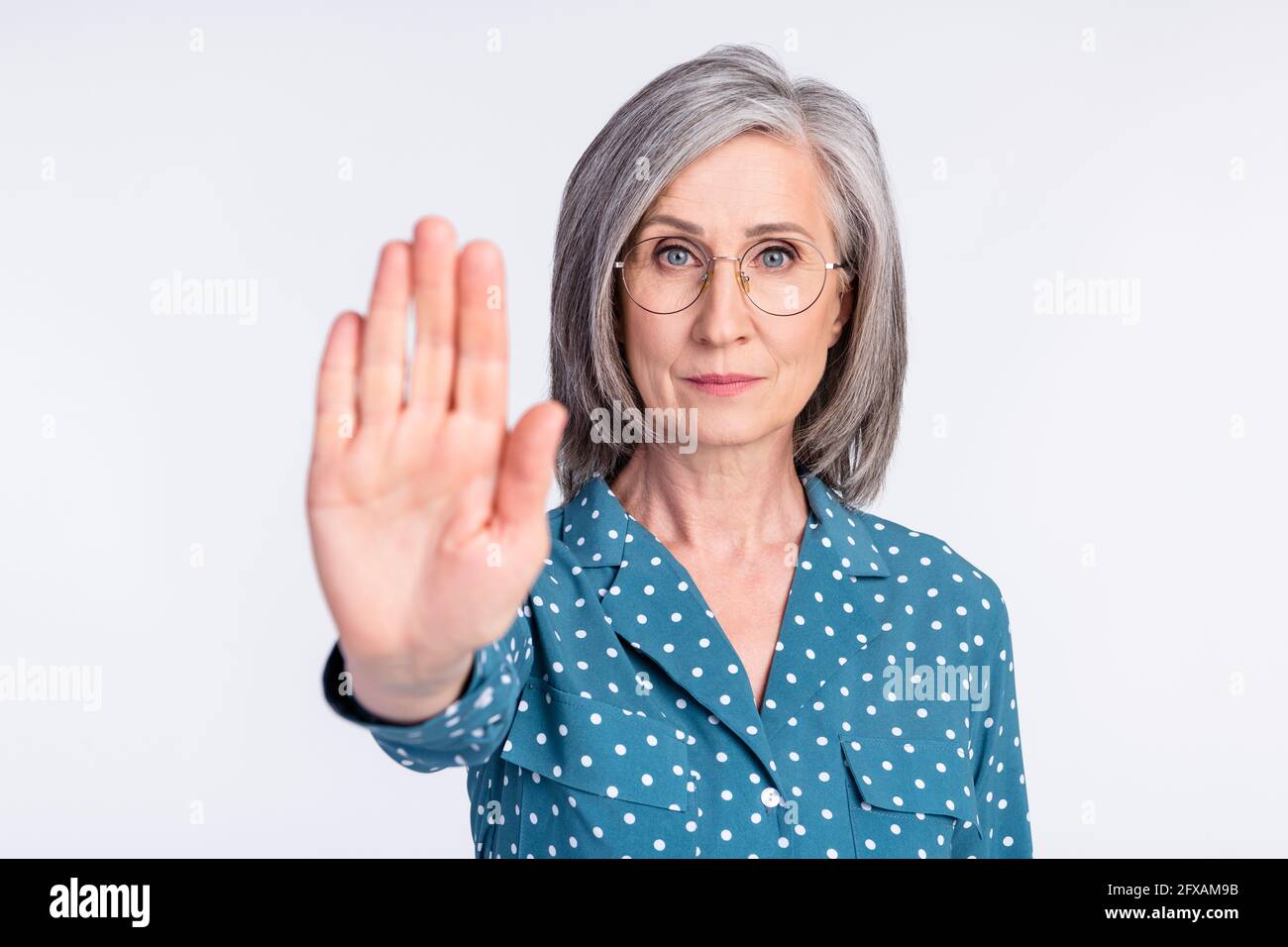 Portrait of attractive serious middle-aged woman showing palm stop sign ...