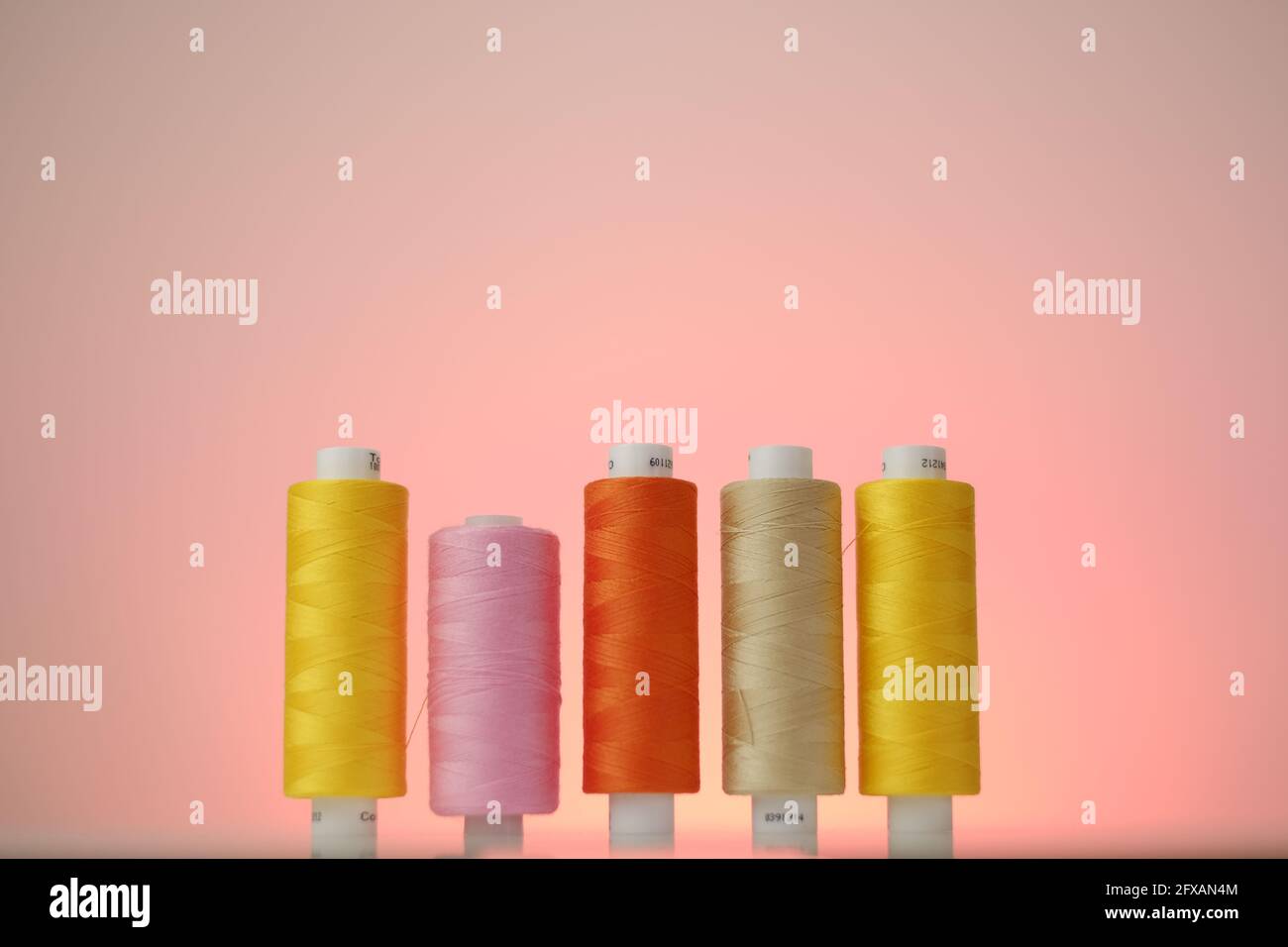 Sewing threads.Multicolored threads set. threads on a pink background ...