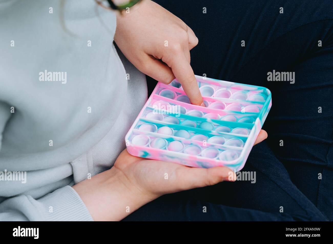 Young Girl Holding pink Pop It Fidget Toy in hands. Teen Playing, Push ...