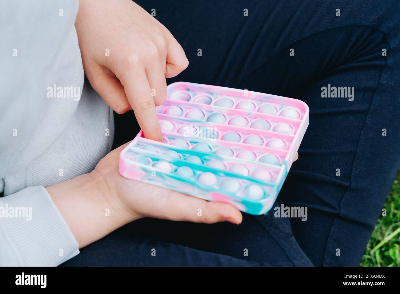 Young Girl Holding pink Pop It Fidget Toy in hands. Teen Playing, Push ...