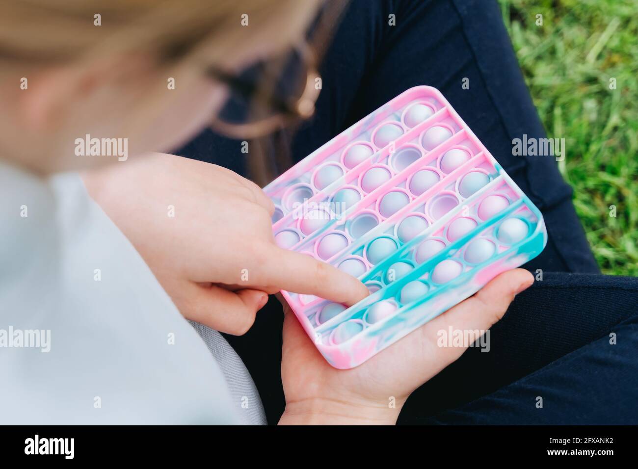 Young Girl Holding pink Pop It Fidget Toy in hands. Teen Playing, Push ...