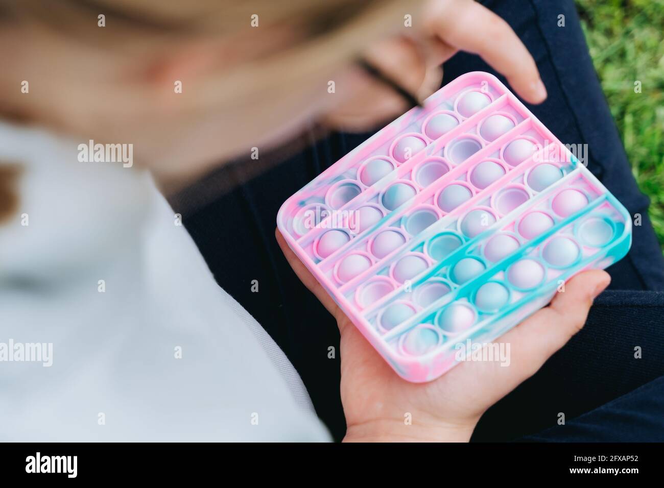 Young Girl Holding pink Pop It Fidget Toy in hands. Teen Playing, Push ...