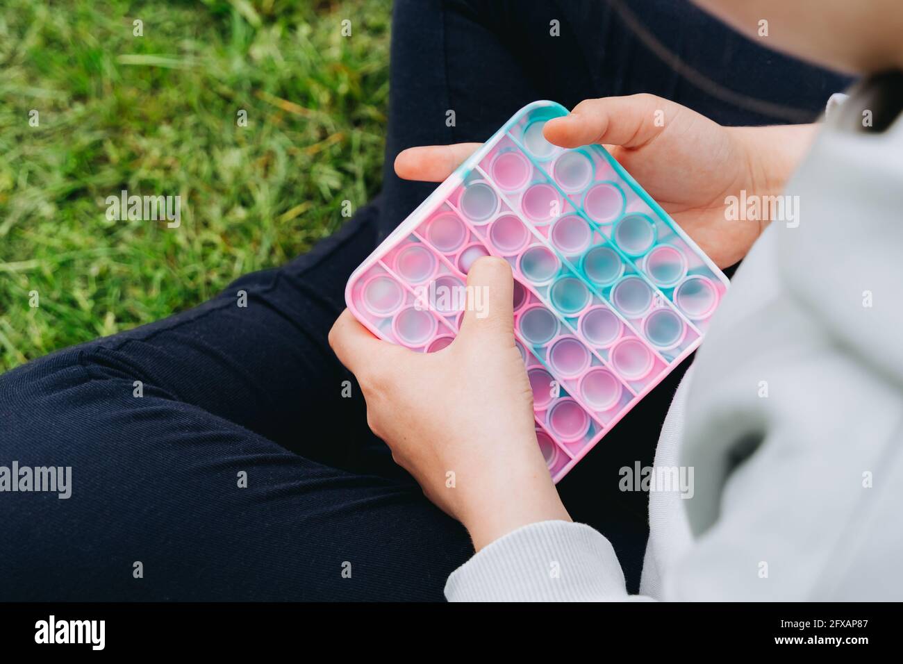 Young Girl Holding pink Pop It Fidget Toy in hands. Teen Playing, Push ...