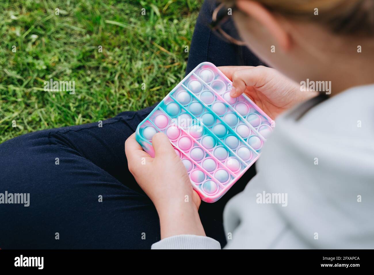 Young Girl Holding pink Pop It Fidget Toy in hands. Teen Playing, Push ...