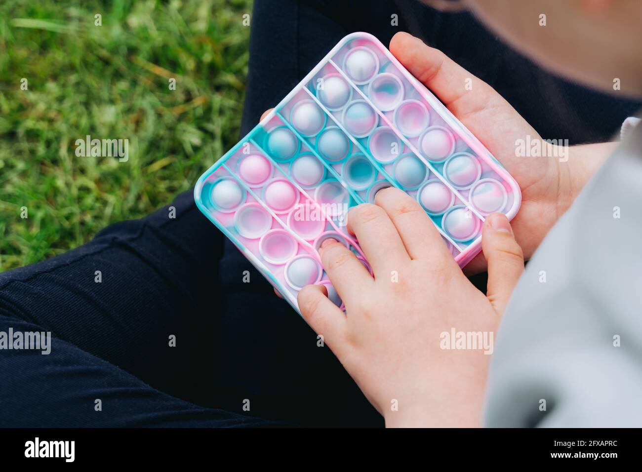 Young Girl Holding pink Pop It Fidget Toy in hands. Teen Playing, Push ...