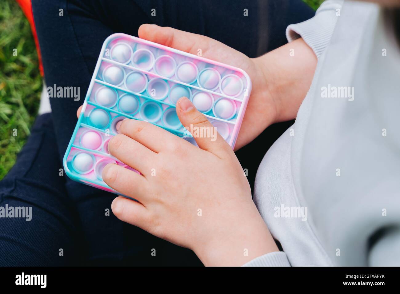 Young Girl Holding pink Pop It Fidget Toy in hands. Teen Playing, Push ...