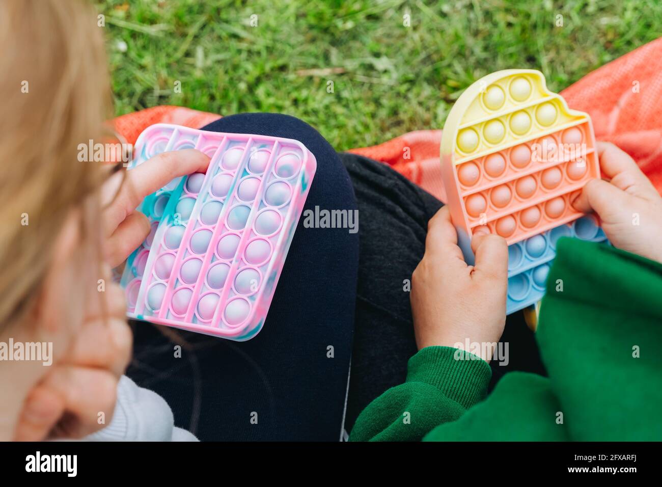 Overhead view of children playing with colorful poppit sensory game ...