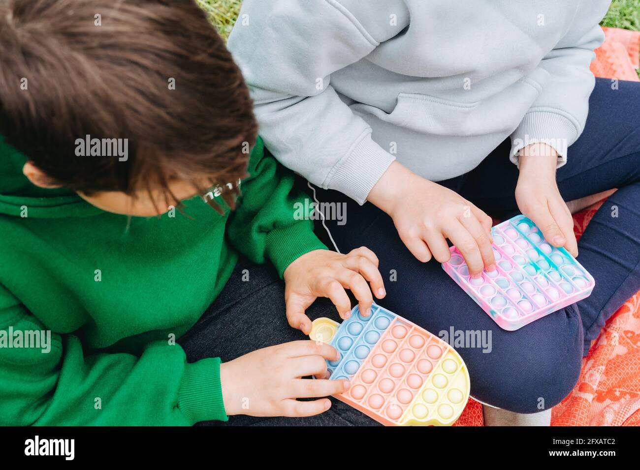 Boy and girl children playing colorful poppit sensory game. Close up of ...