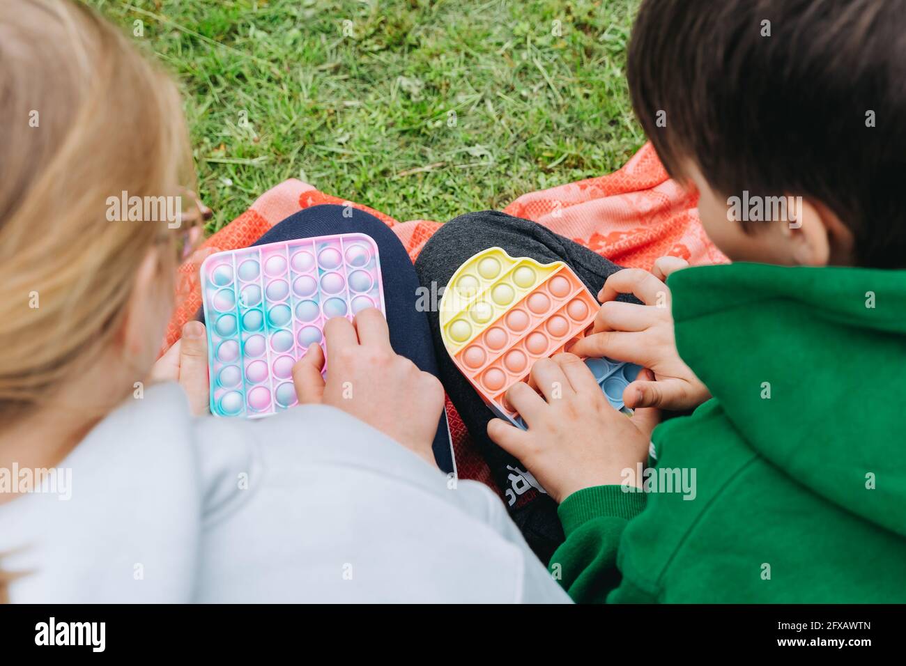 Overhead view of children playing with colorful poppit sensory game ...