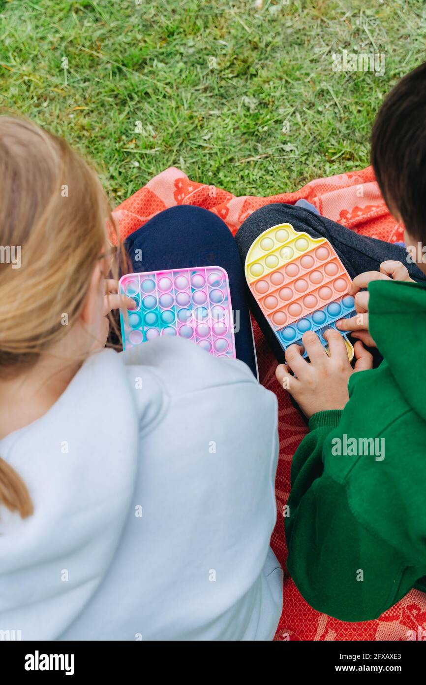 Top view of children playing with colorful poppit sensory game together ...