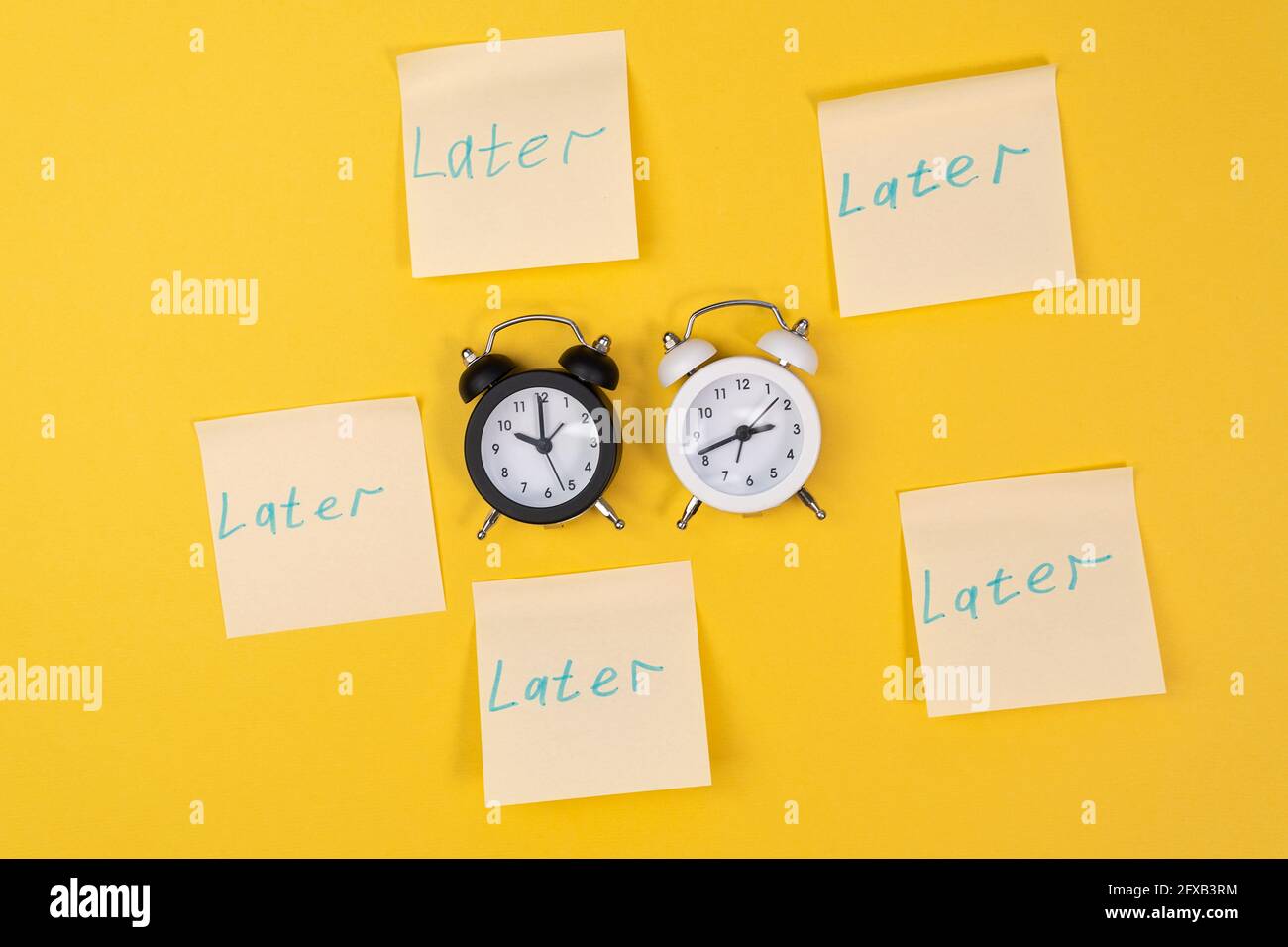 Alarm clock with a sticky note with text later. Procrastination, delay ...