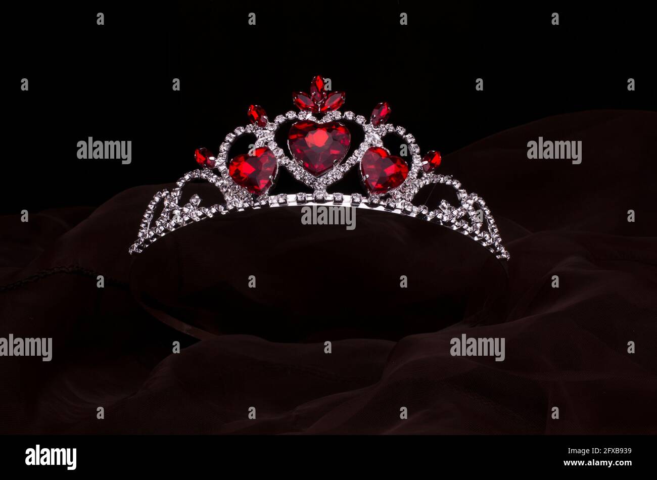 silver crown with hearts, rubies and diamonds isolated on the fabric ...