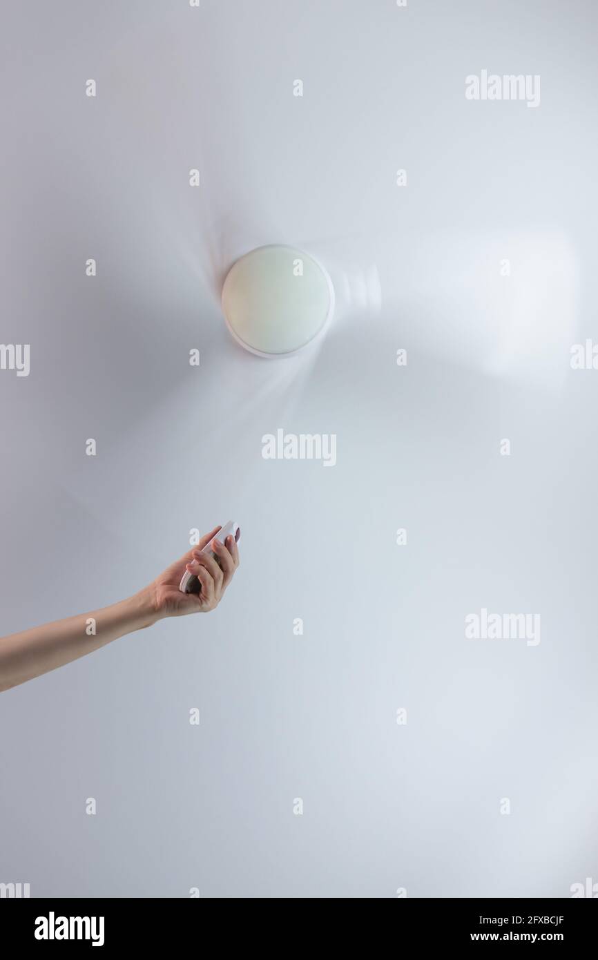 Close-up of hand holding remote control of white ceiling fan. Hand ...